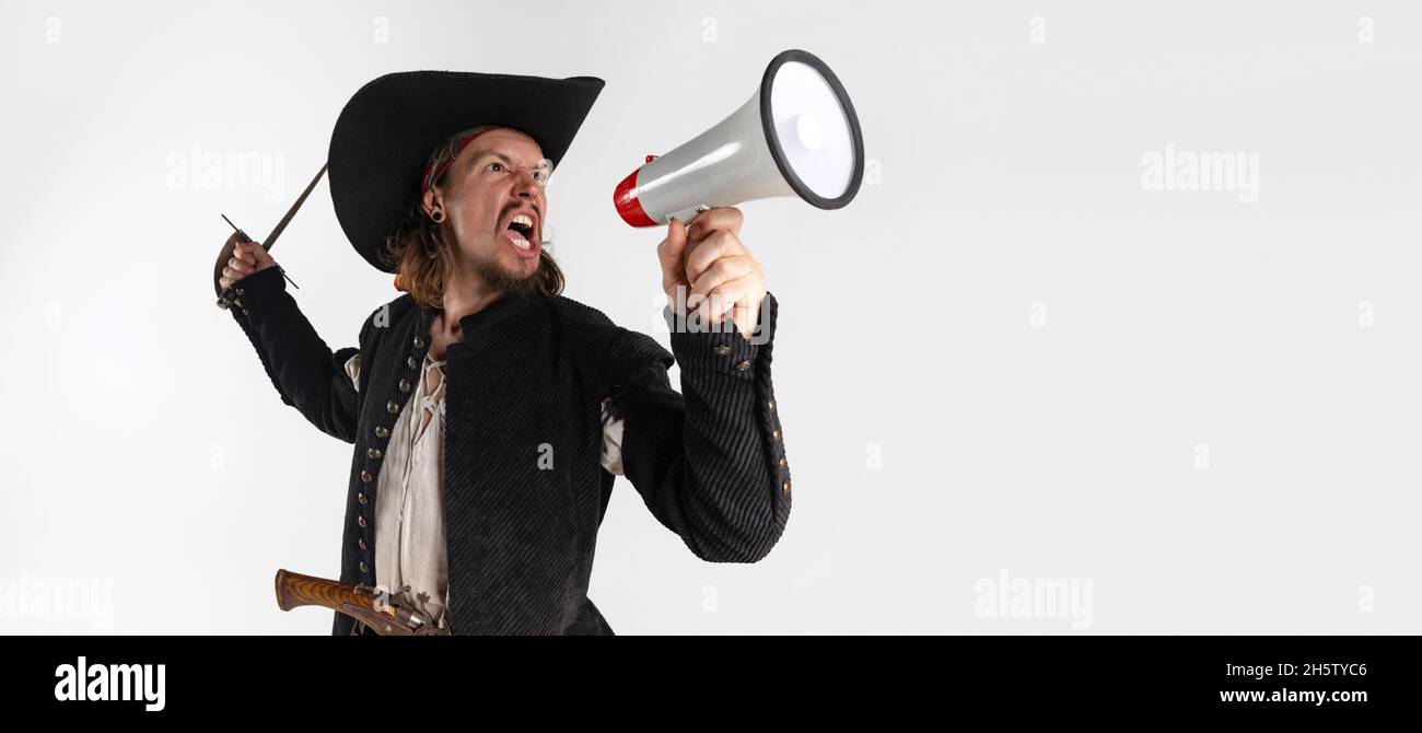 Cropped portrait of man, pirate in vintage costume raising sword and ...