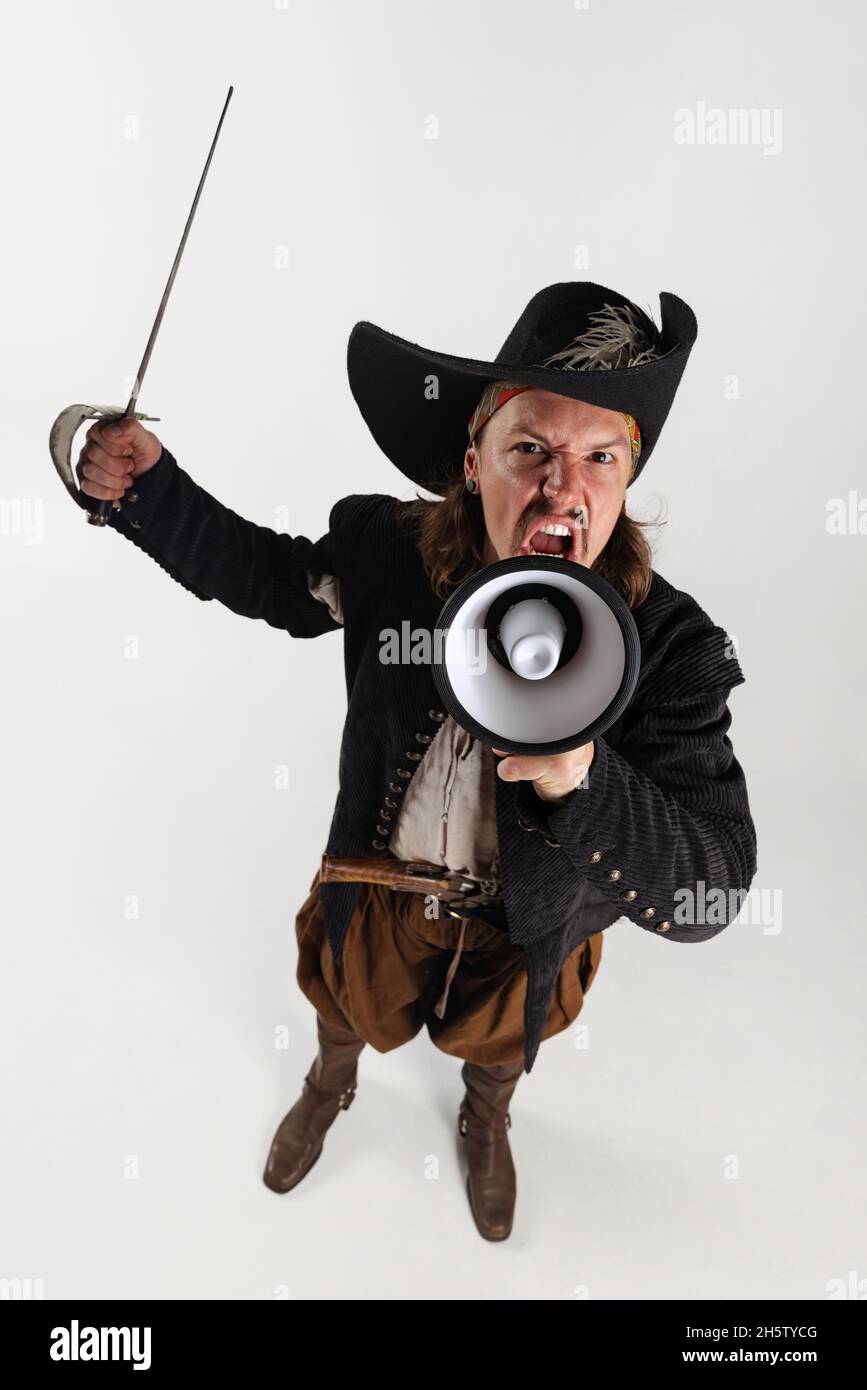 Full-length portrait of man, pirate in vintage costume raising sword ...