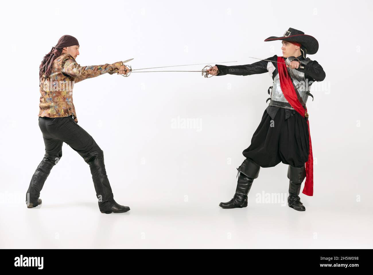 Full-length portrait of two men in vitage costumes musketeer and pirate ...