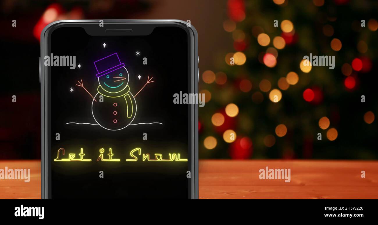 Image of let it snow text and snowman in smartphone over christmas tree ...