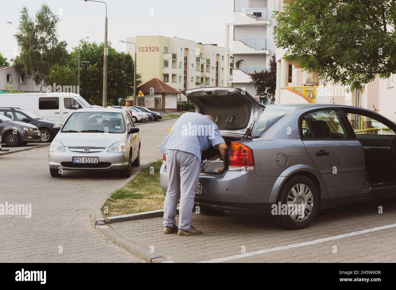 POZNAN, POLAND - Jul 10, 2018: A man unpacking a trunk of a parked car ...