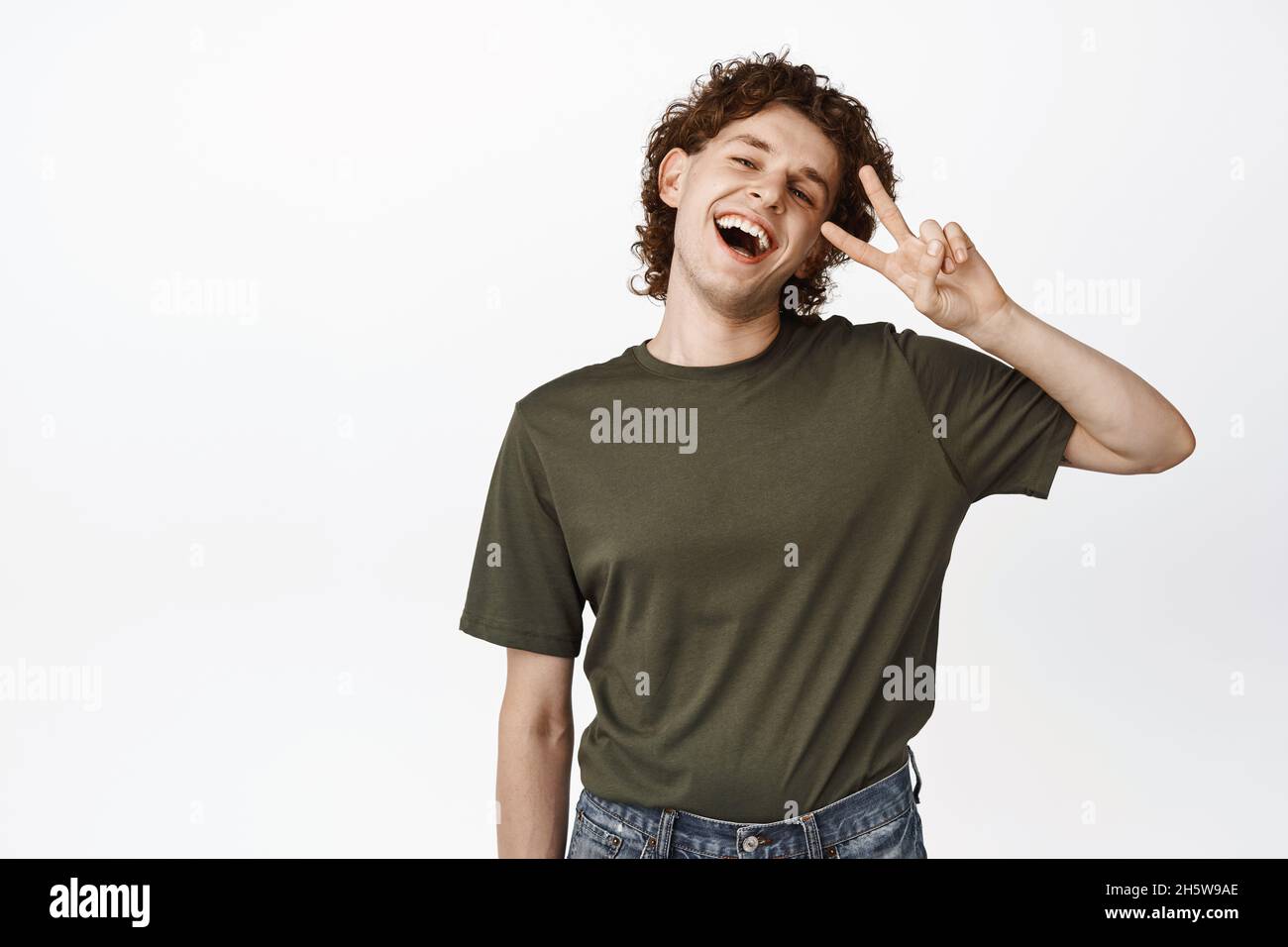Positive happy young guy showing peace, salute gesture and laughing ...