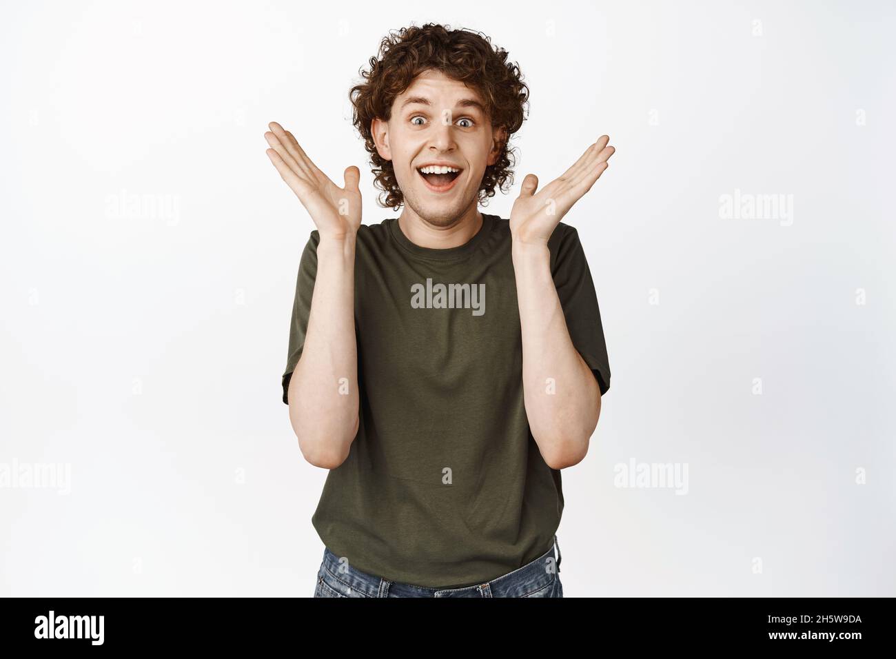 Portrait of excited young man with curly hair, looking fascinated and ...