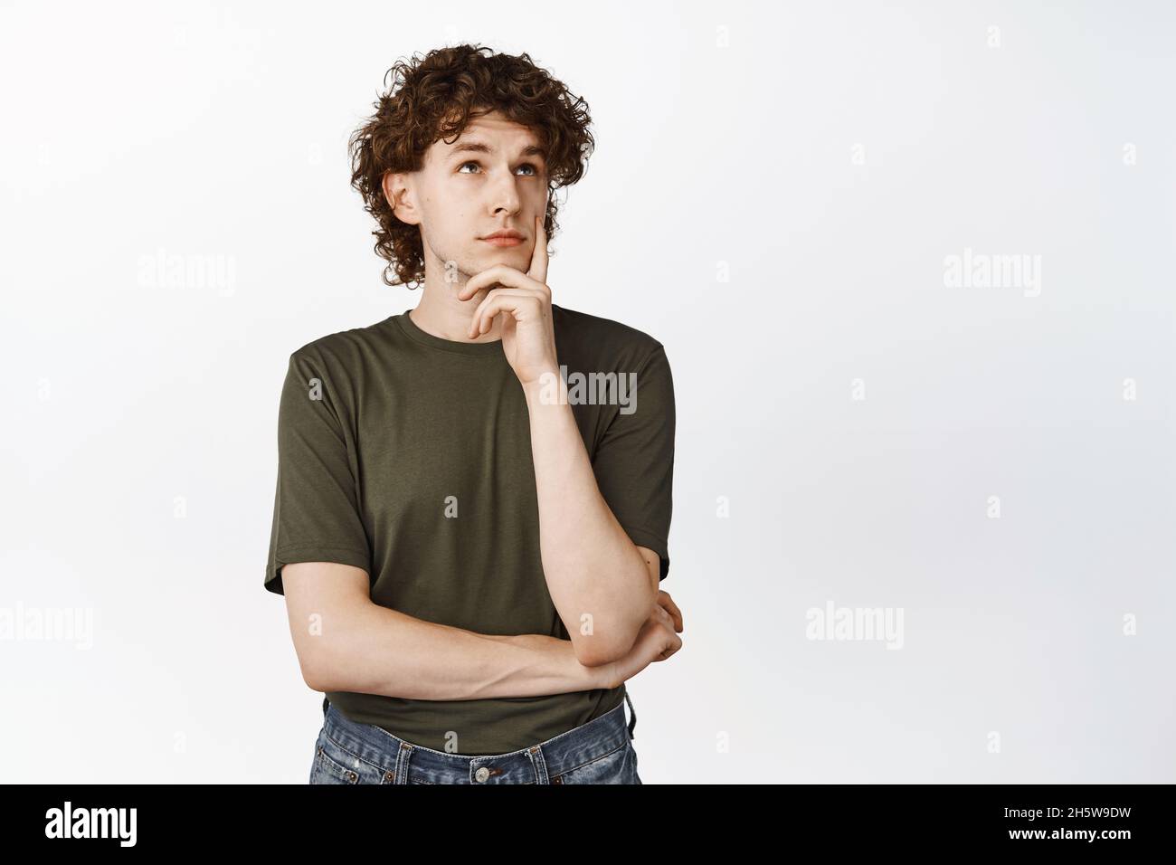 Young curly guy thinking, looking up thoughtful, making decision ...
