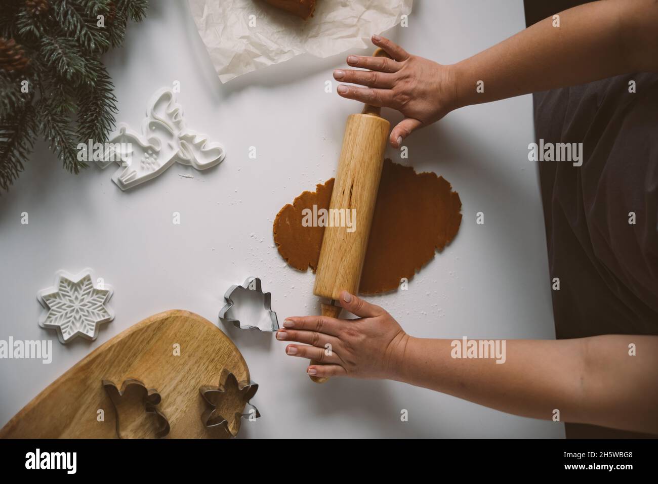 Female hands roll out raw ginger dough with a rolling pin on a white ...