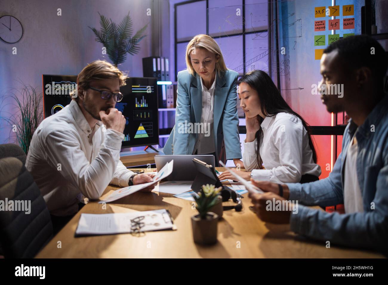 Female team leader in business clothes having briefing with multi ...