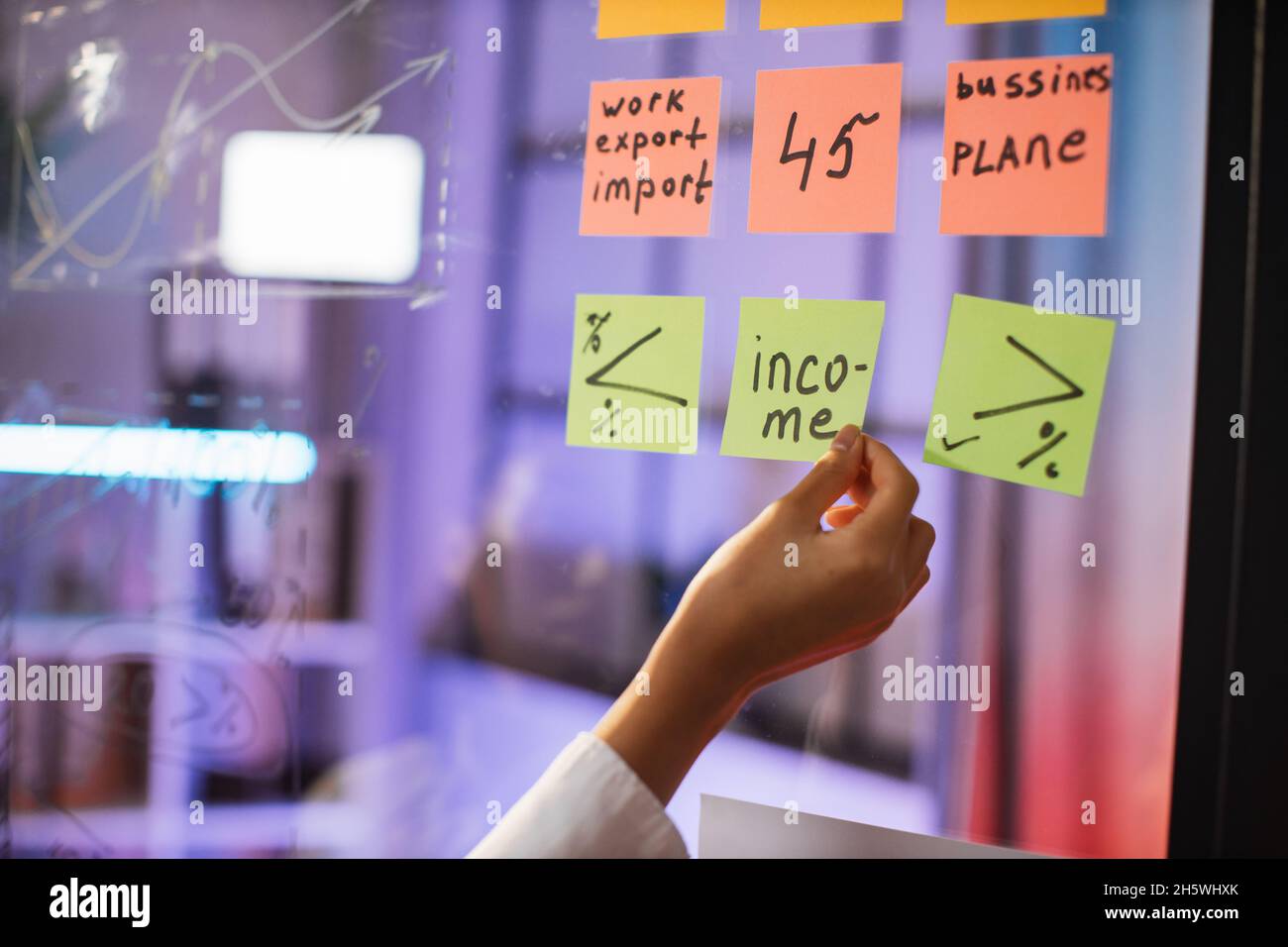 Close up of female hand putting paper stickers on transparent board ...