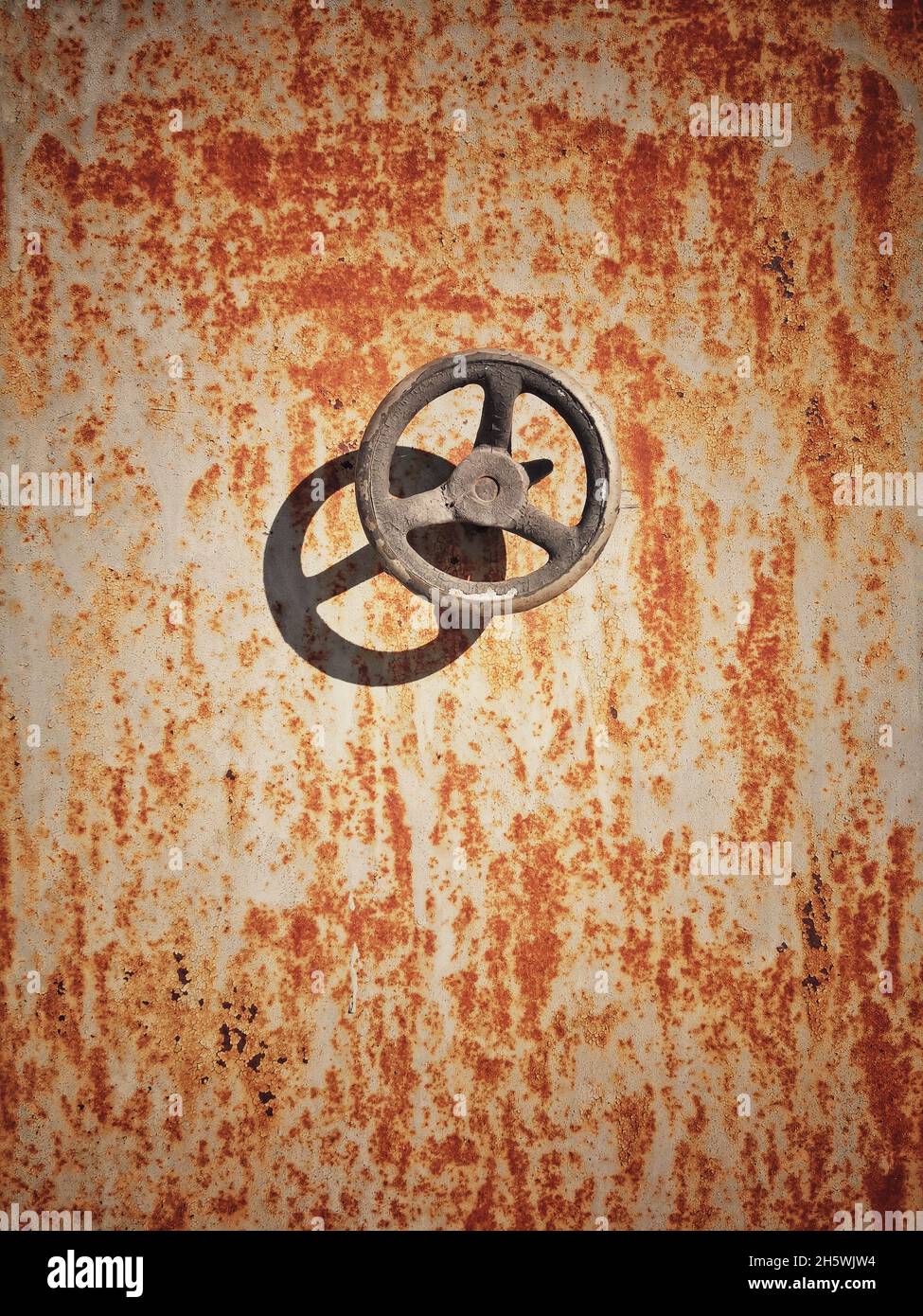 Old damaged and rusty iron oil pipe valve wheel on a metal wall Stock ...