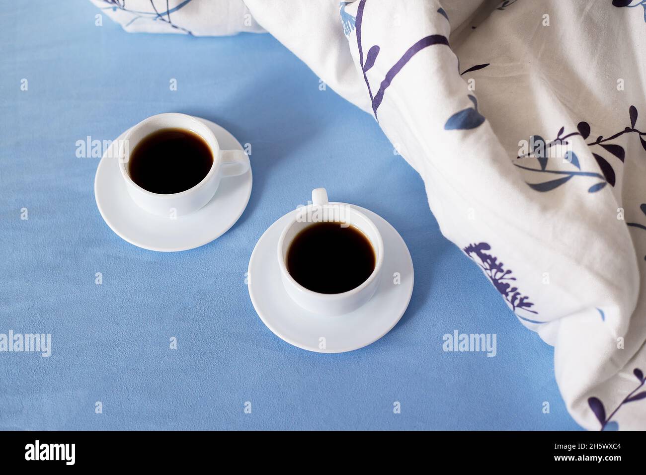 Two white cups of coffee are in bed Stock Photo - Alamy