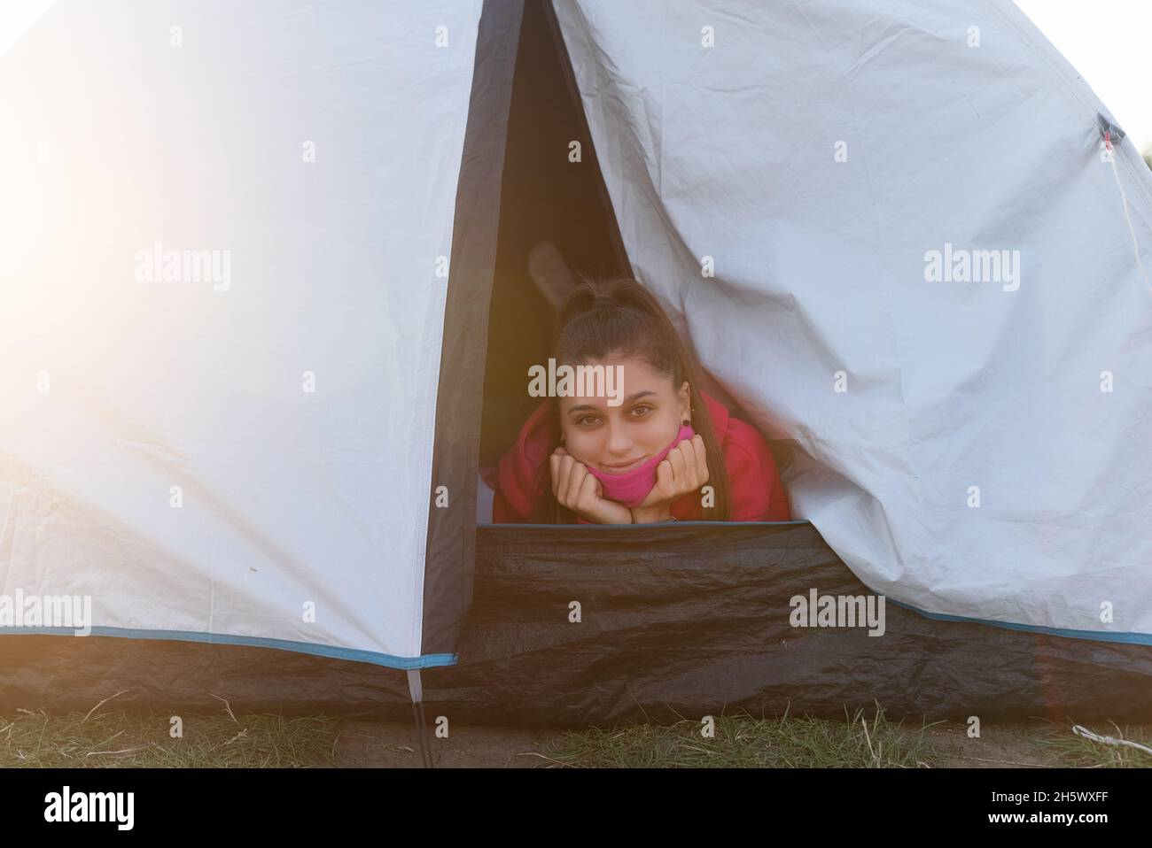 Young woman peeking out of the tent with only her head sticking out ...
