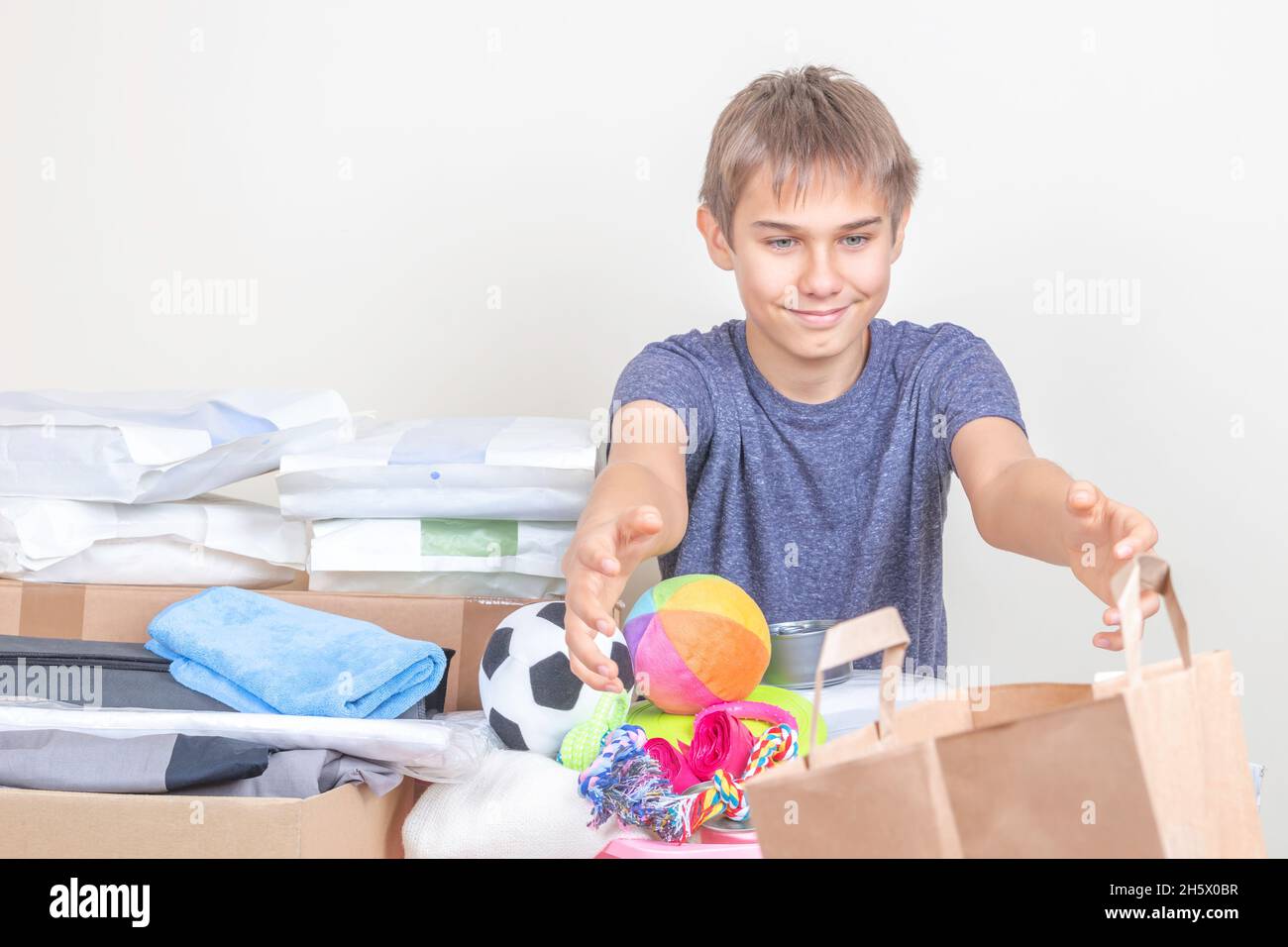 Teenage boy extending hands, stretching out arms to take bag with ...