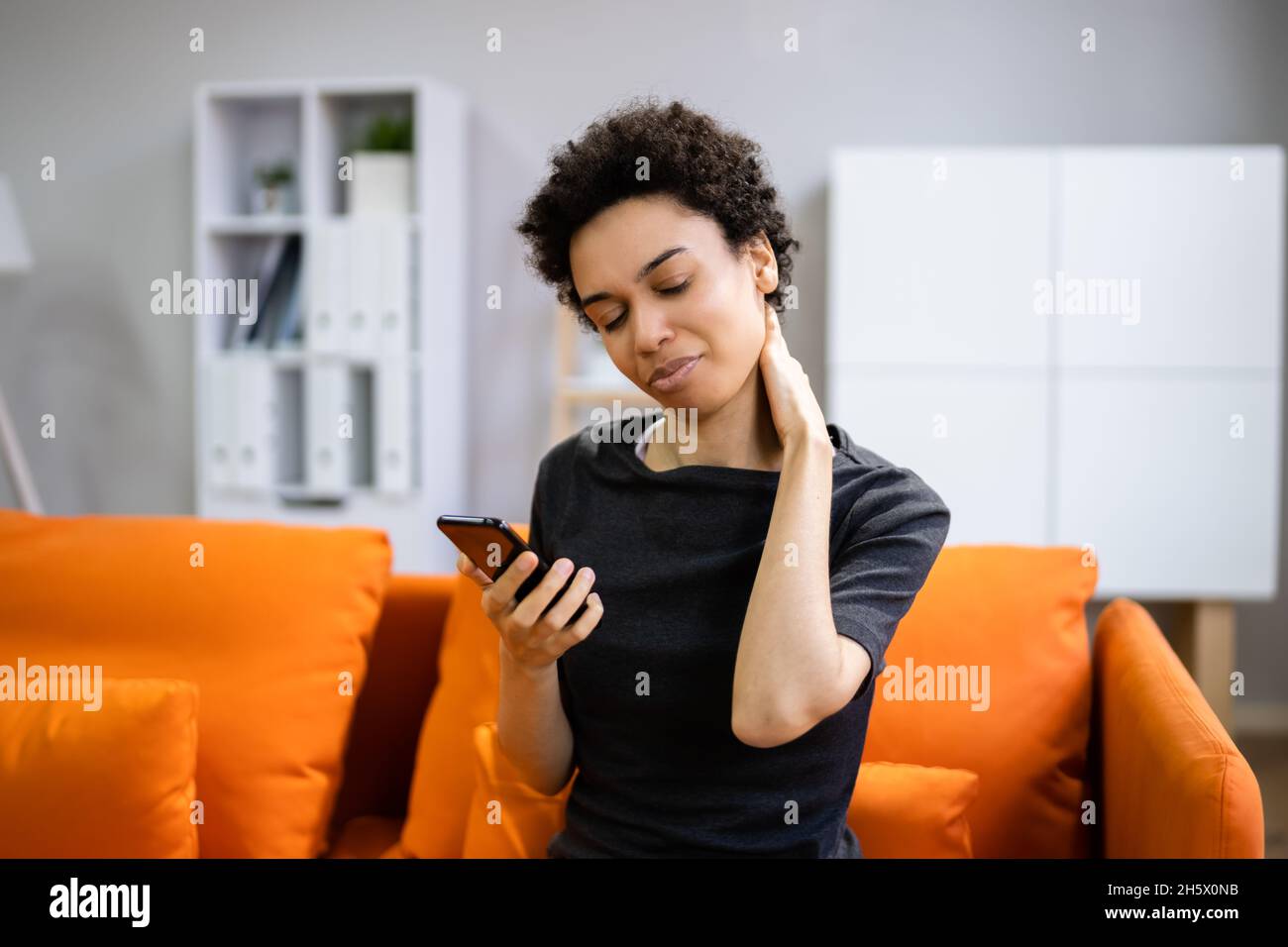 Woman With Neck Pain Sitting Using Mobile Phone Stock Photo - Alamy