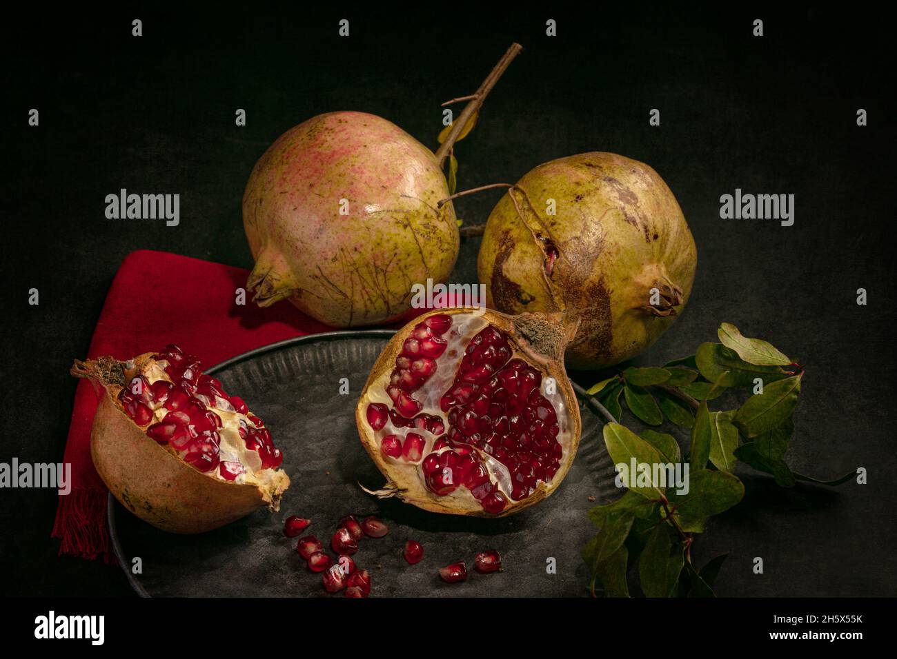 Pomegranate and open pomegranate in a plate on a dark table Stock Photo ...