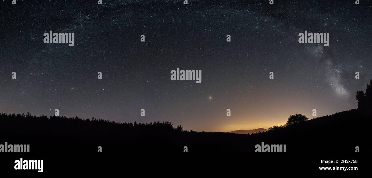 Milky Way arc on the top of the mountain and with the lights of ...