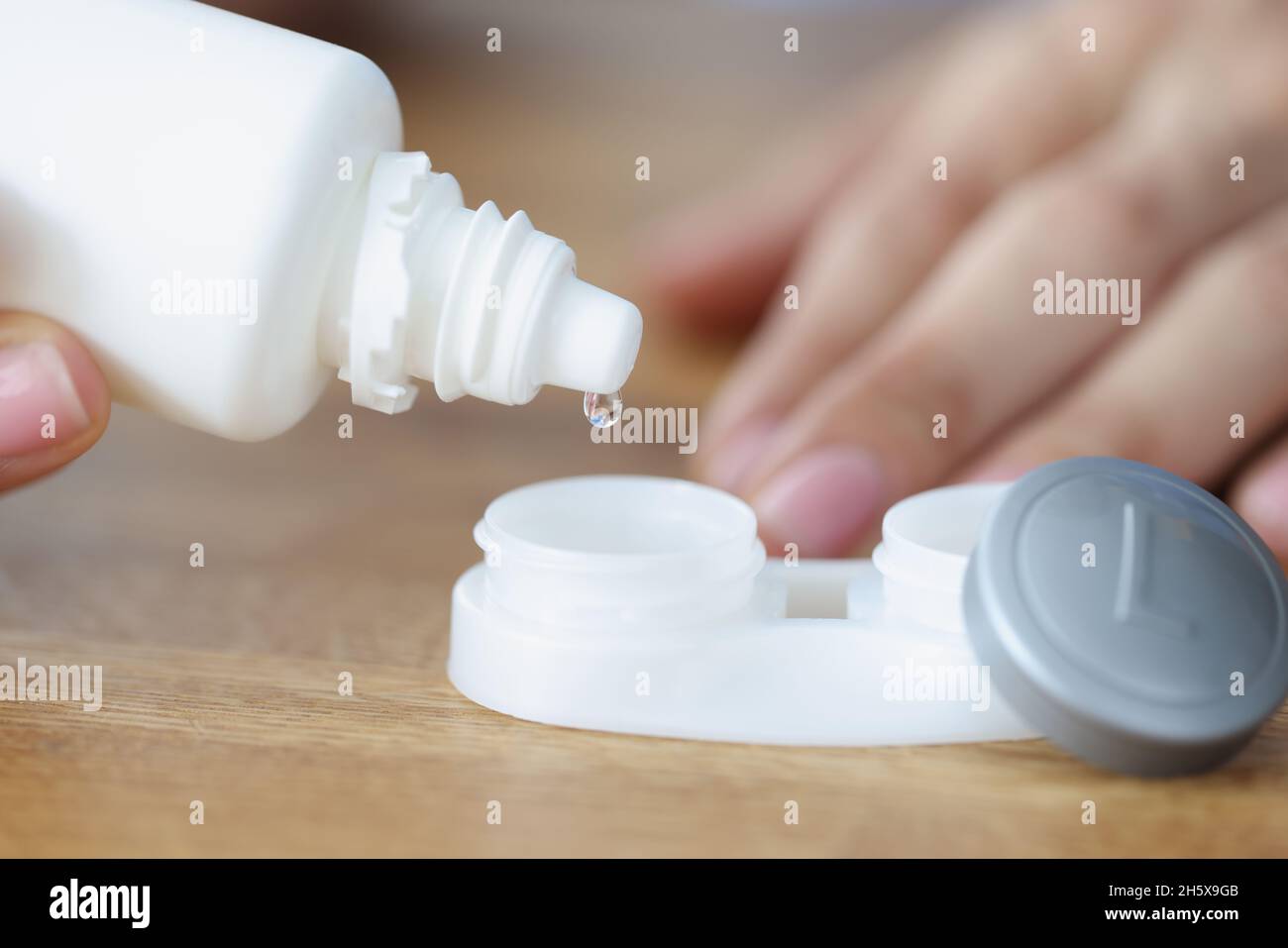 Female hand pouring lens liquid into plastic container closeup Stock ...