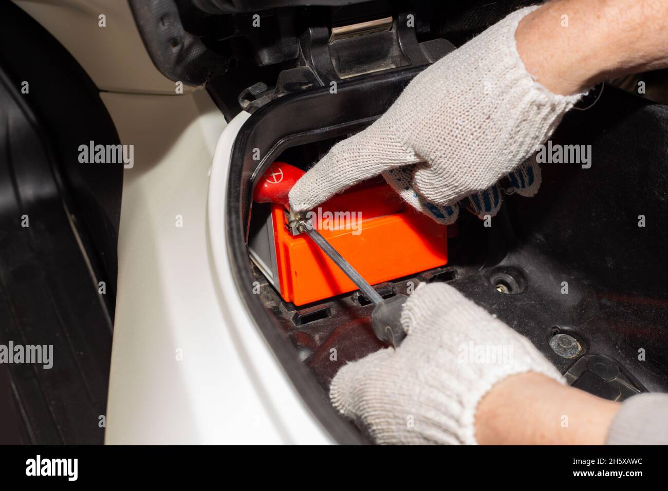 The car mechanic removes the battery from the motorbike. Battery repair ...
