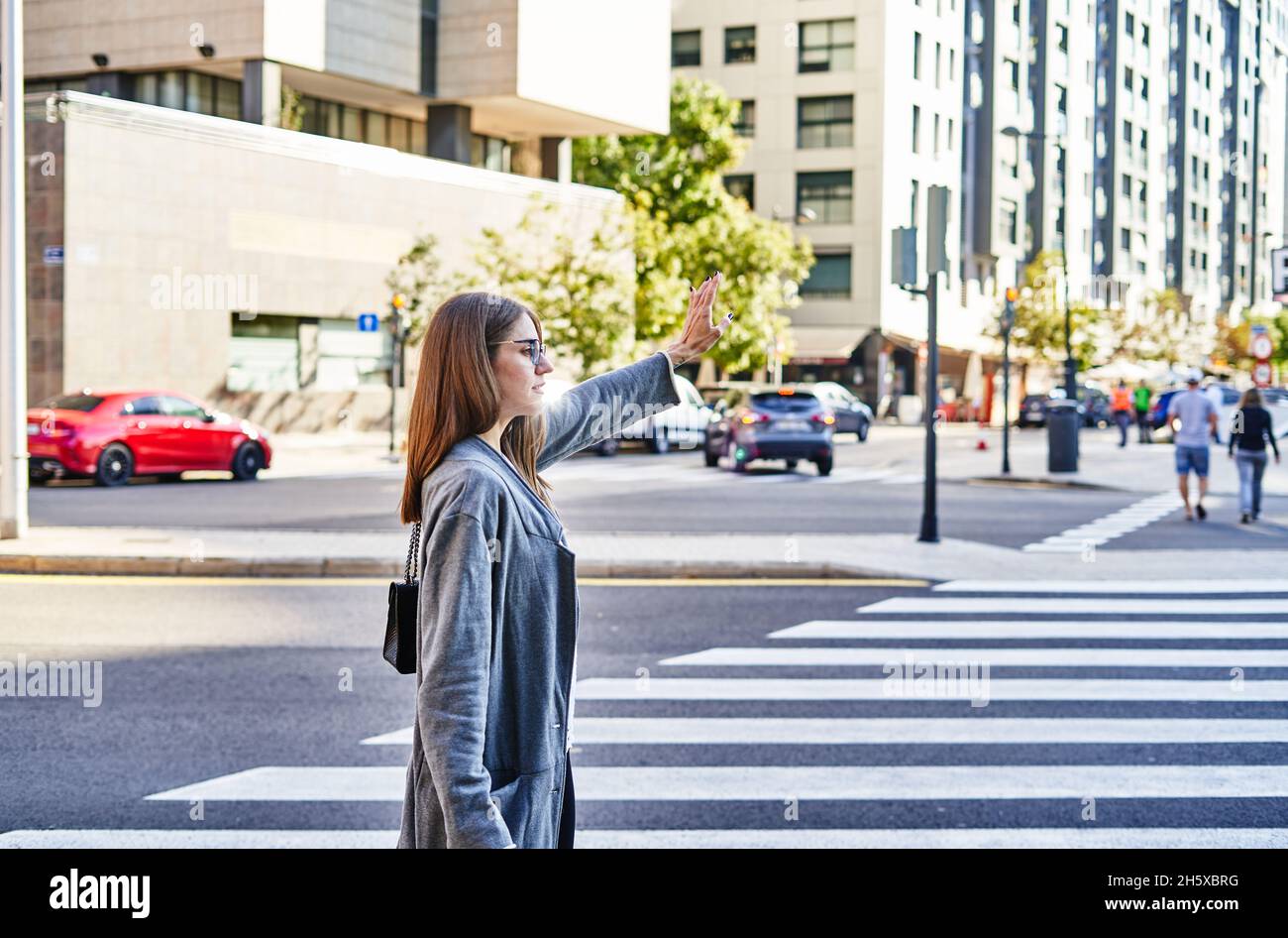 Side view of female with outstretched arm catching cab while standing ...