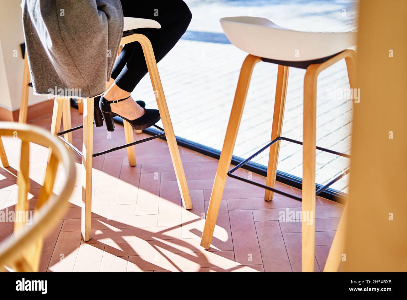 High angle of crop anonymous female in coat and high heels sitting on ...