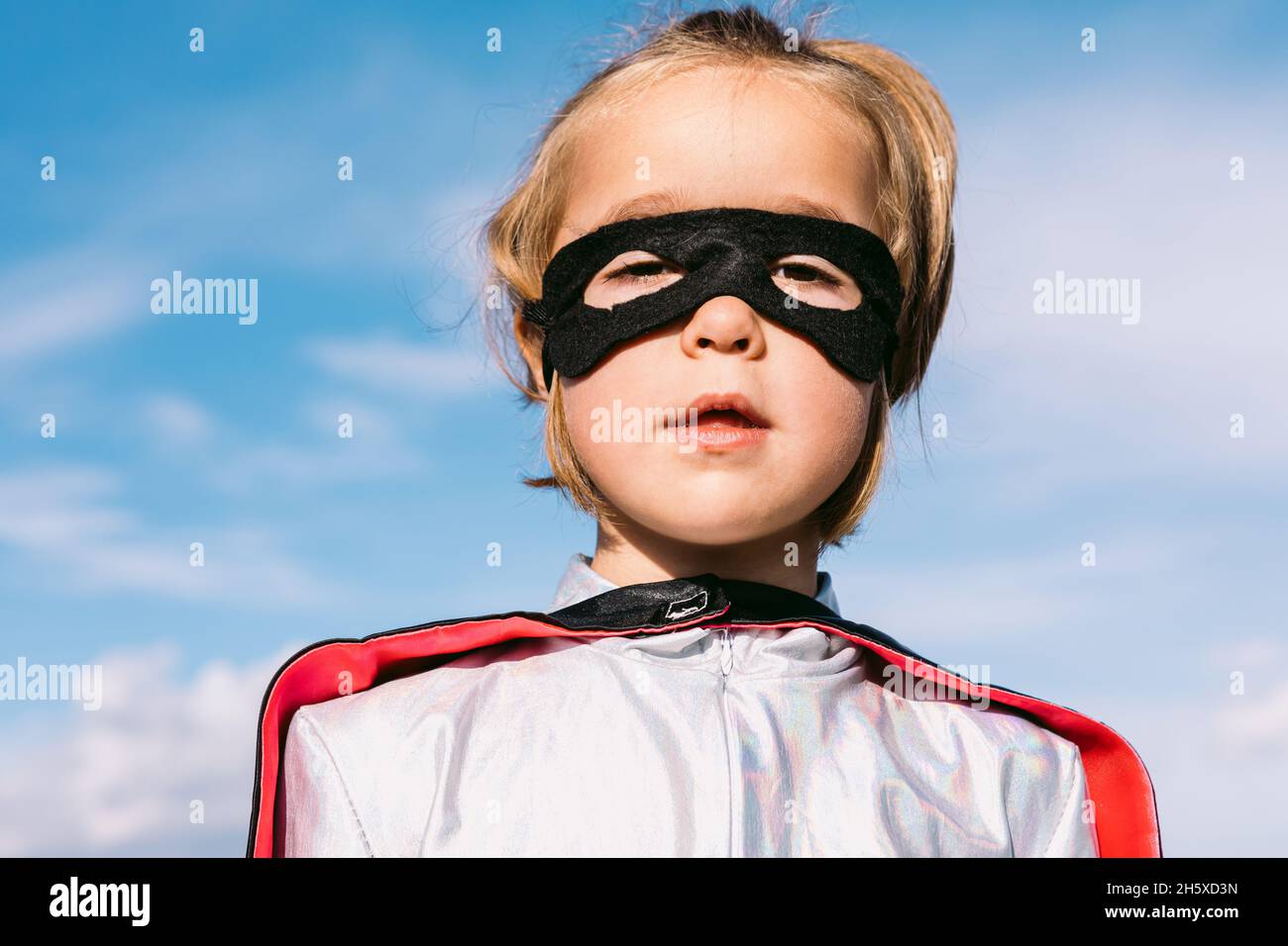 Cute kid wearing masquerade superhero costume and eye mask standing ...