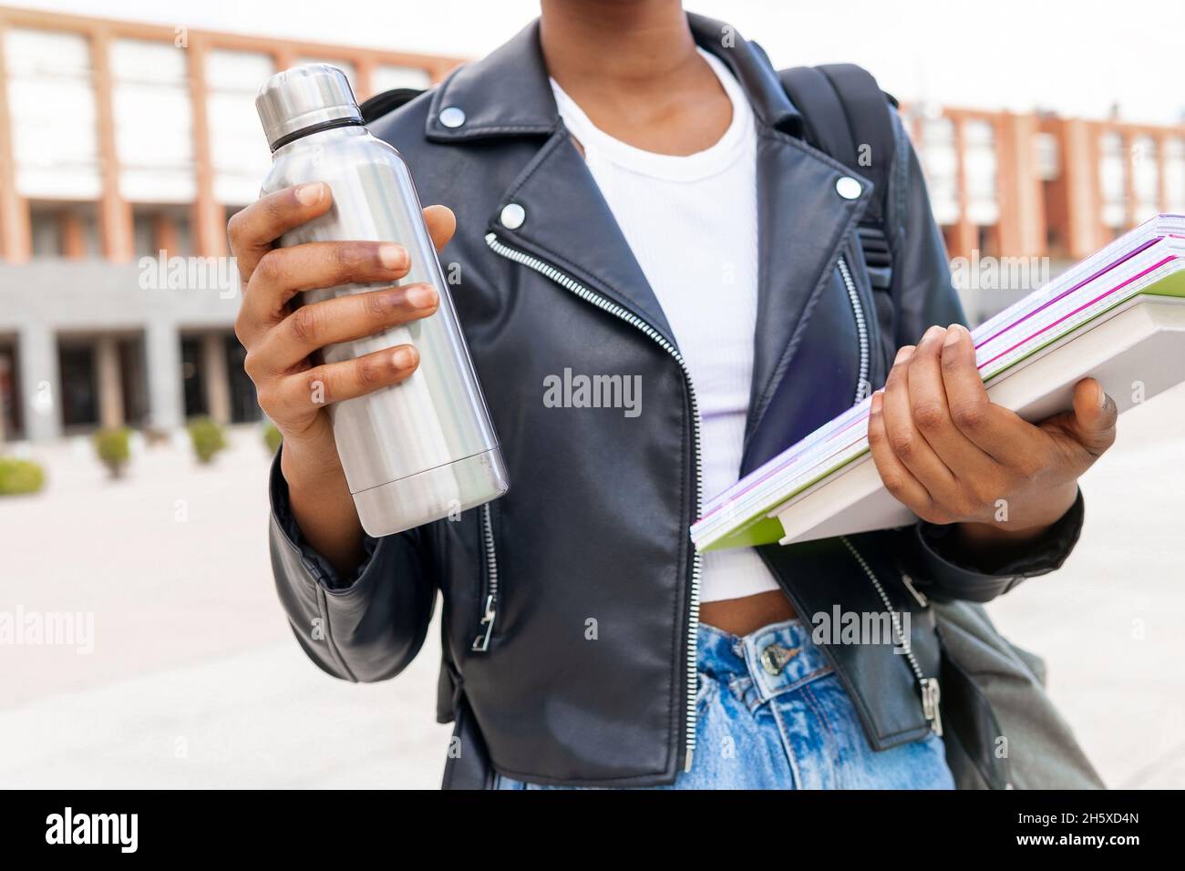 Anonymous African American female student with thermos and bunch of ...