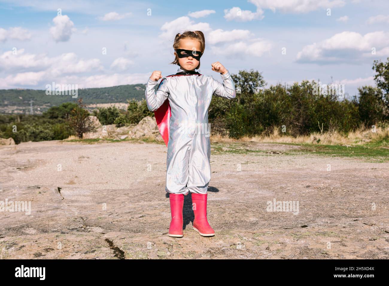 Full body of small girl in superhero costume raising outstretched fists ...