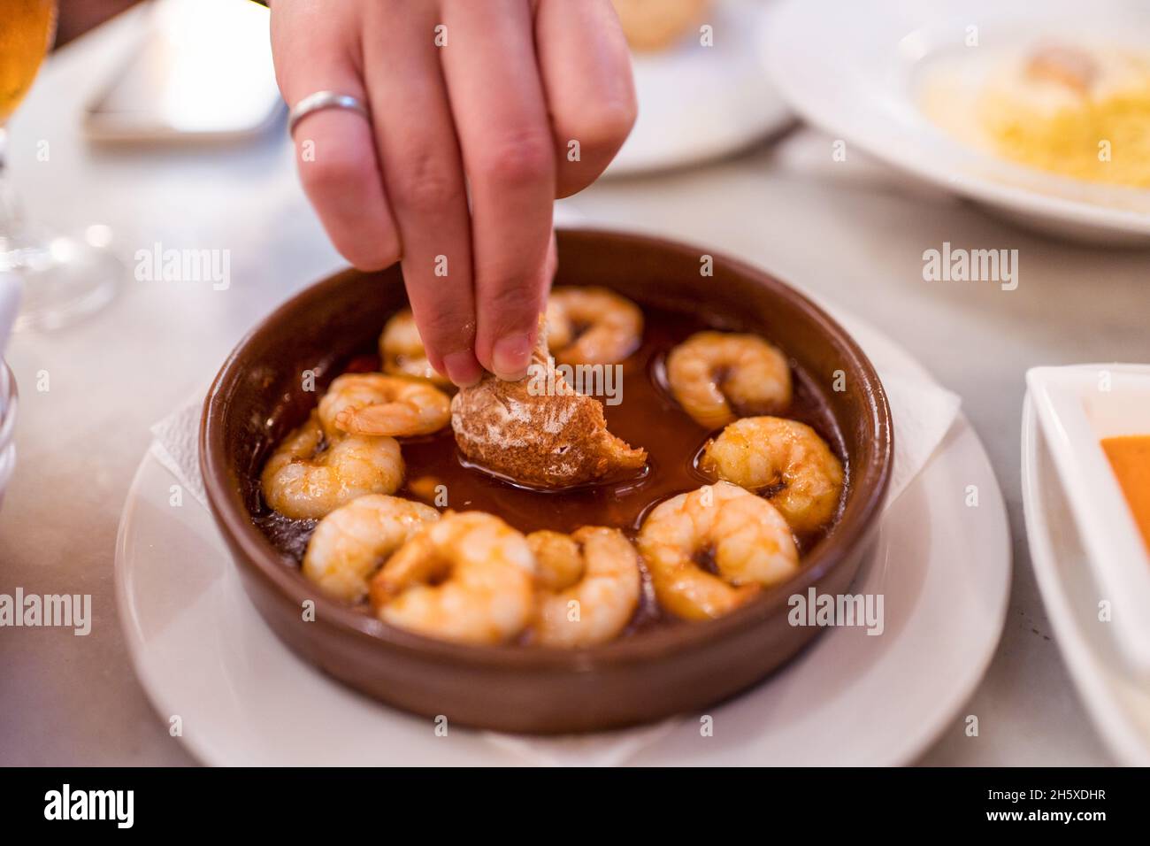 From above of crop unrecognizable Woman dipping bread piece into sauce ...