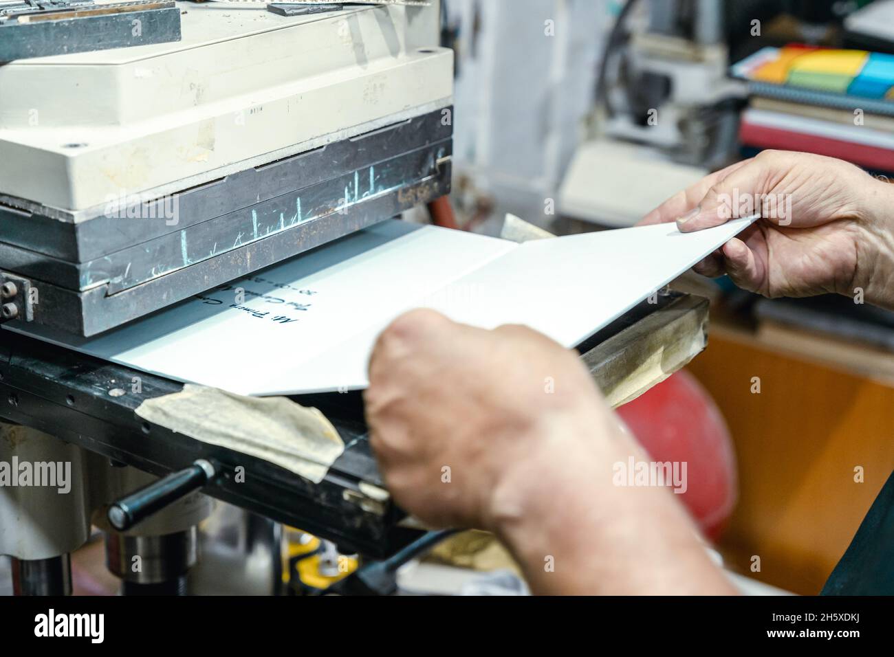 Crop unrecognizable artisan putting papers into aged printing press ...