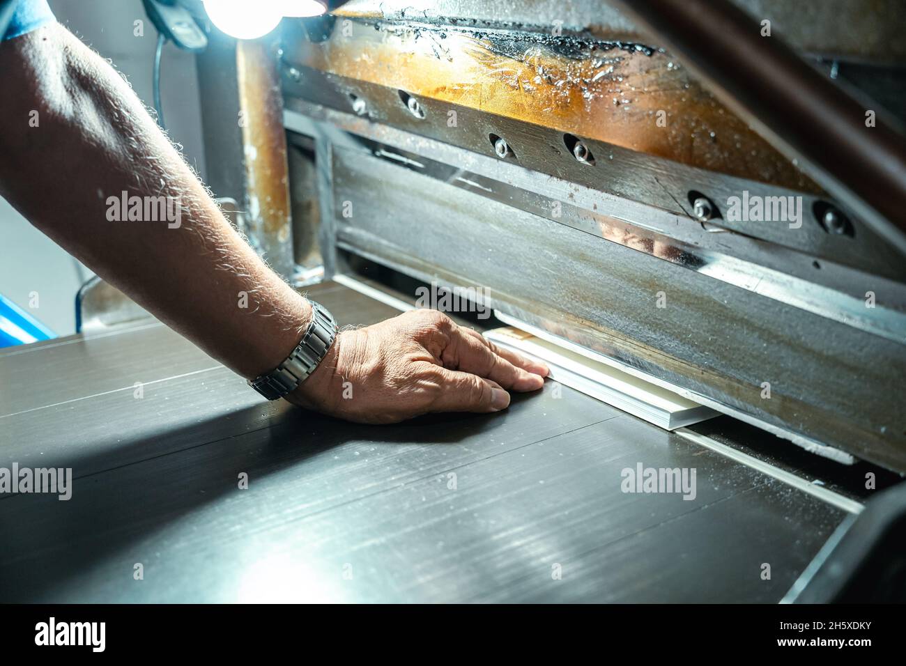 Crop unrecognizable aged male artisan putting paper sheets into metal ...