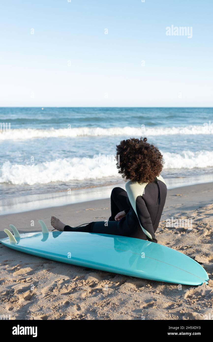 Back view full body of anonymous barefoot female surfer in wetsuit ...