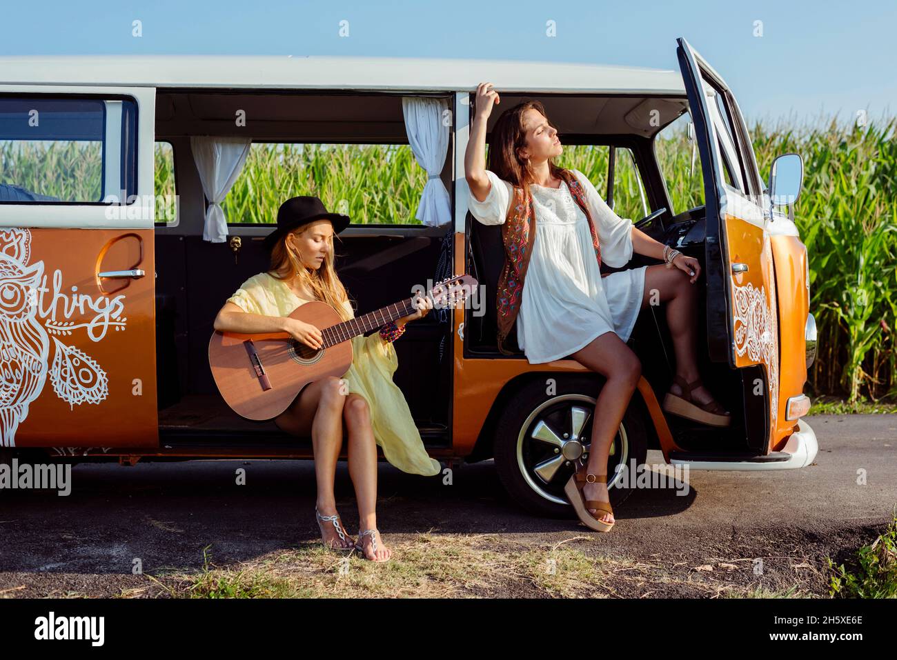 Two pretty girls dressed in summer clothes having fun outside a van and ...