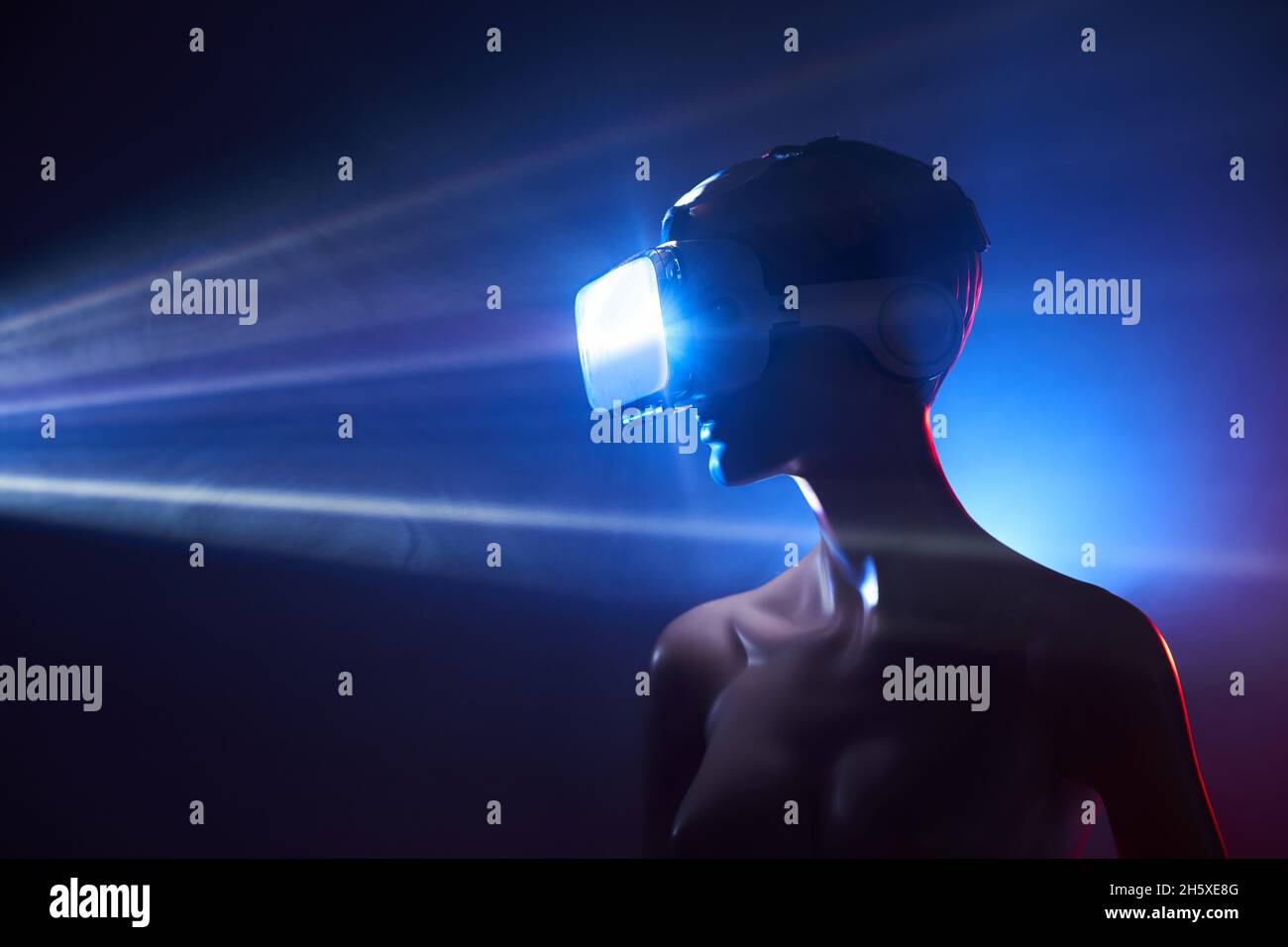 Dummy of Woman in futuristic VR goggles placed under bright projection ...