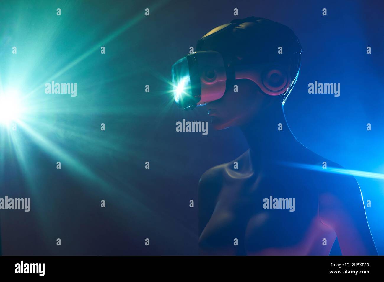 Dummy of Woman in futuristic VR goggles placed under bright projection ...