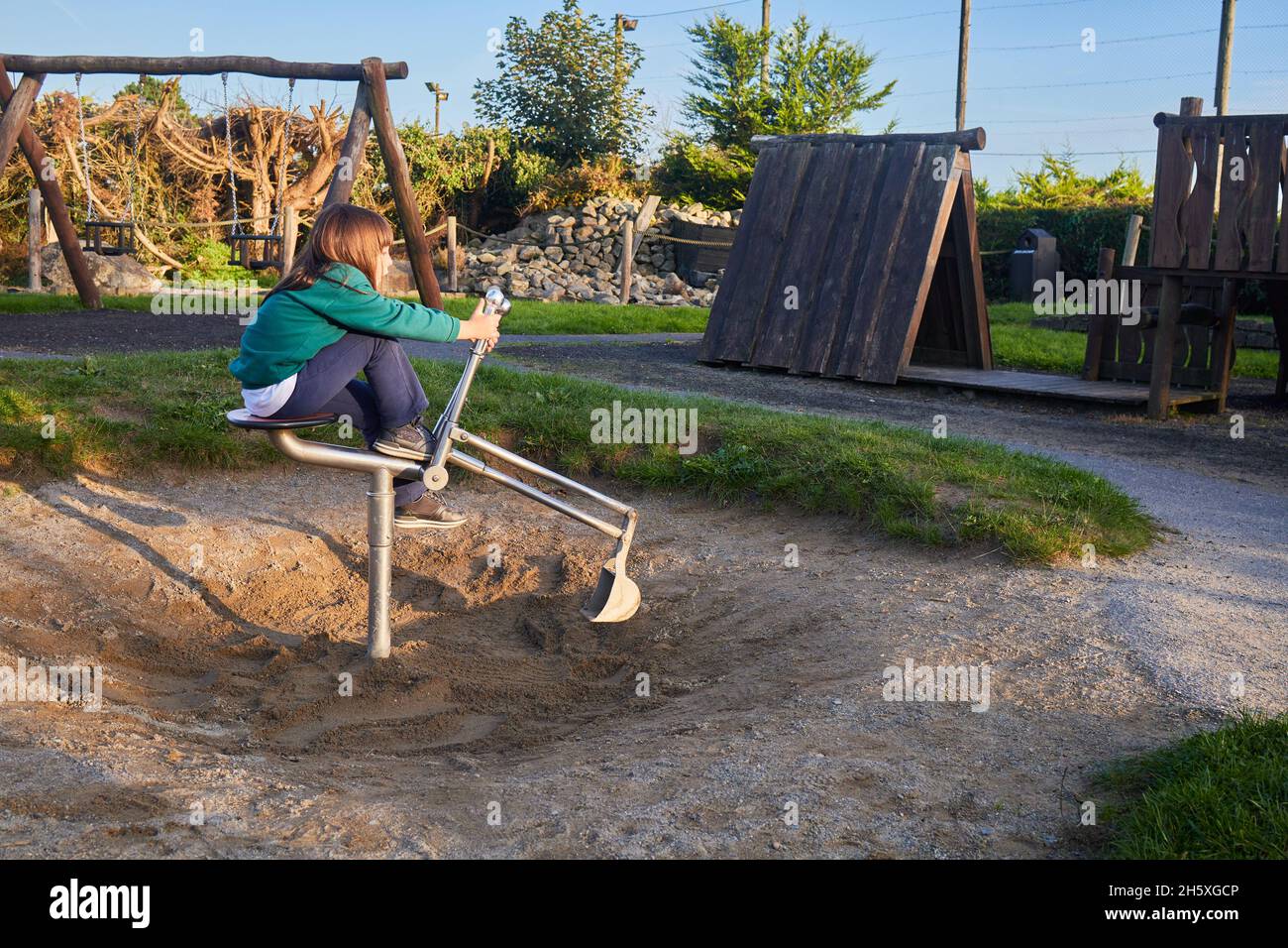 bulldozer of a playground with a girl playing, with beautiful sunset ...