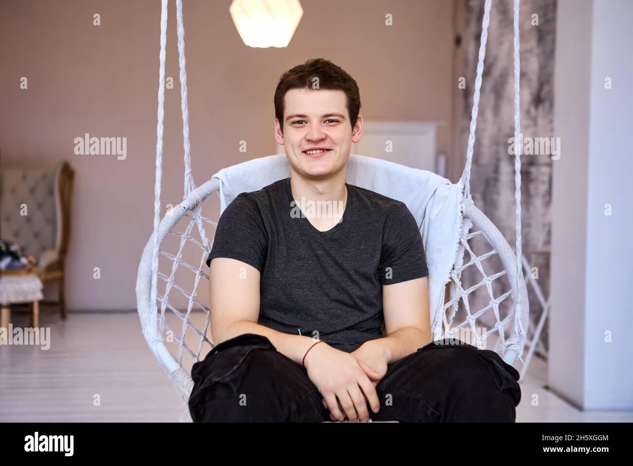 Smiling 23 years old man in hanging chair indoors Stock Photo - Alamy
