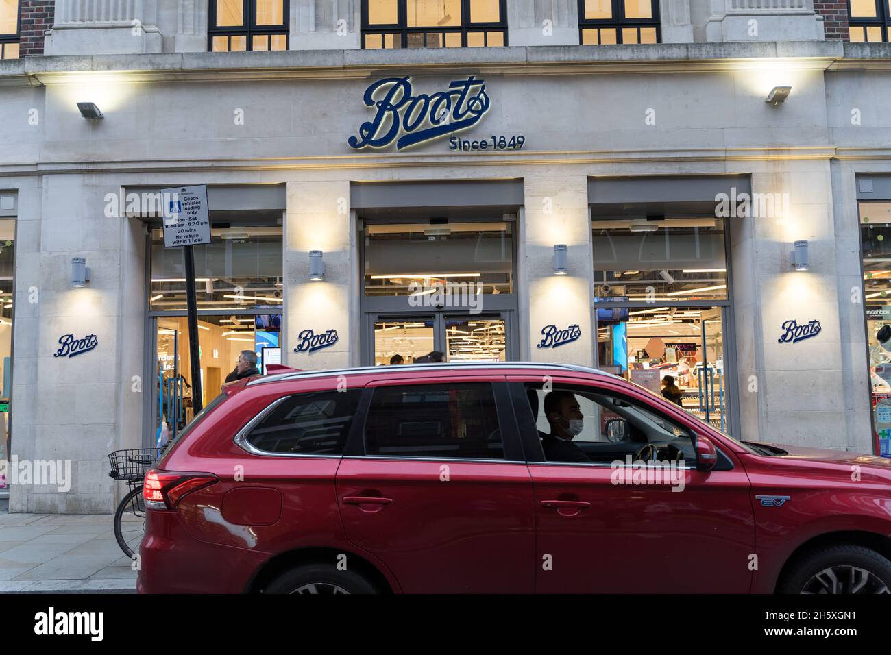 red car past the shop front of Boots store at Covent Garden London ...