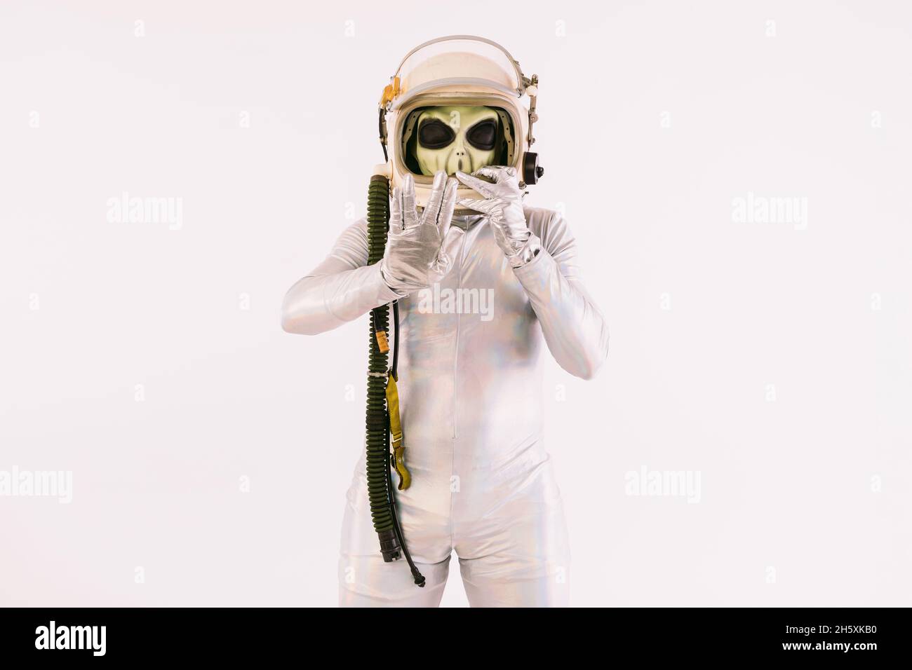 Person dressed in silver suit and green alien mask, wearing a cosmonaut ...