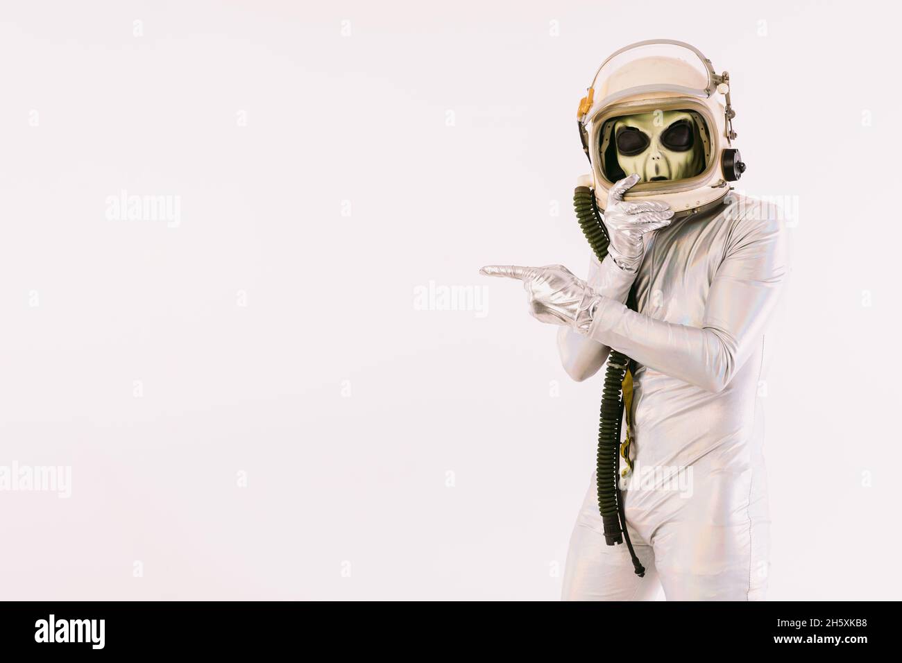 Person dressed in silver suit and green alien mask, wearing a cosmonaut ...
