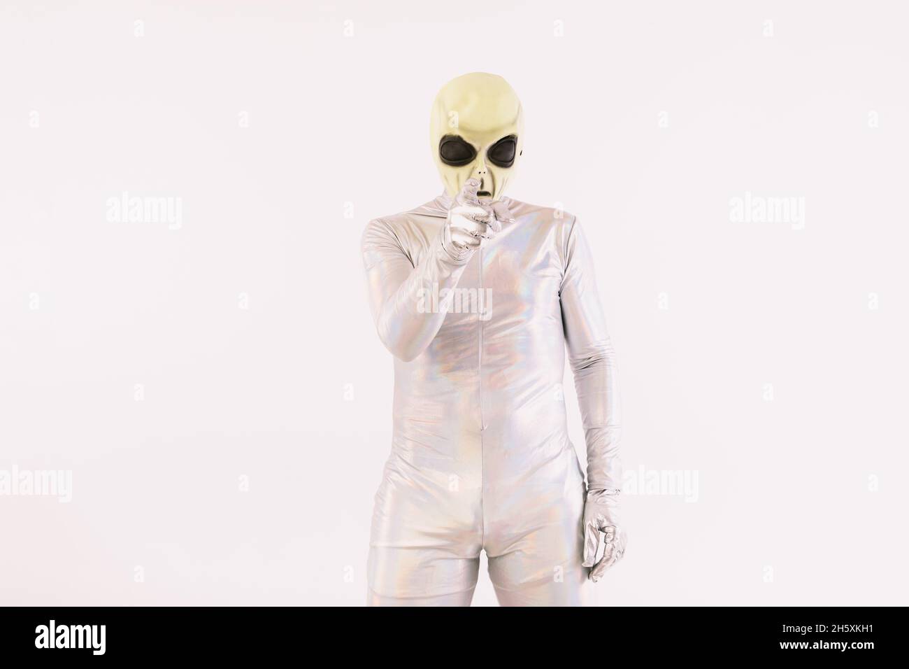 Person dressed in silver suit and green alien mask pointing at camera ...