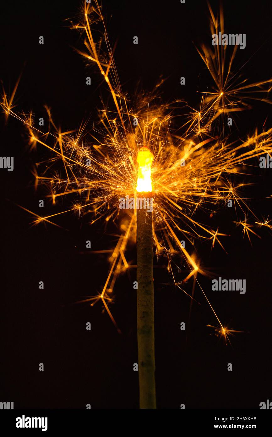 Vertical shot of a burning sparkling bright firework stick in the ...