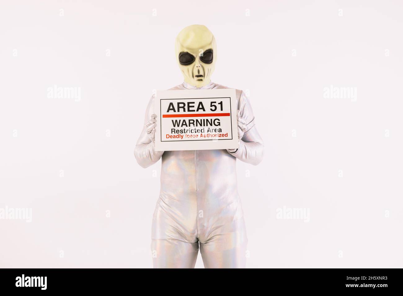 Person dressed in silver suit and green alien mask, holding an Area 51 ...