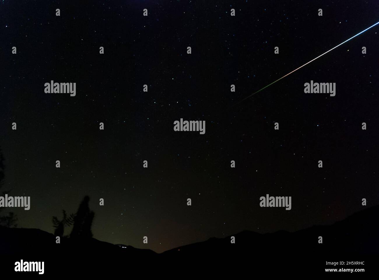 Night scene with starry sky with long perseid meteor shower running ...