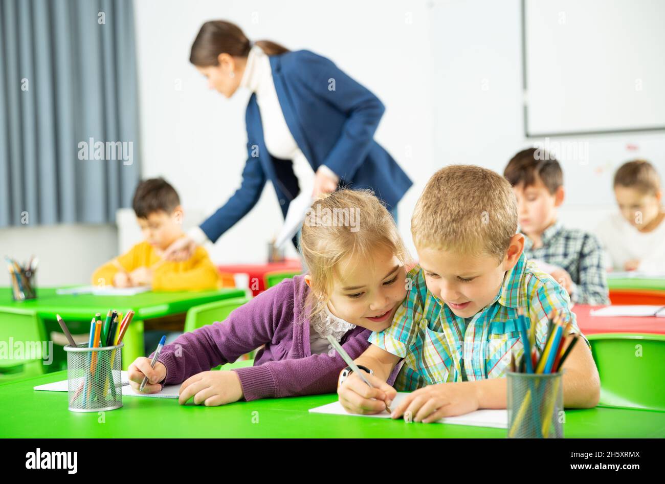 Happy schoolchildren chatting during lesson Stock Photo - Alamy