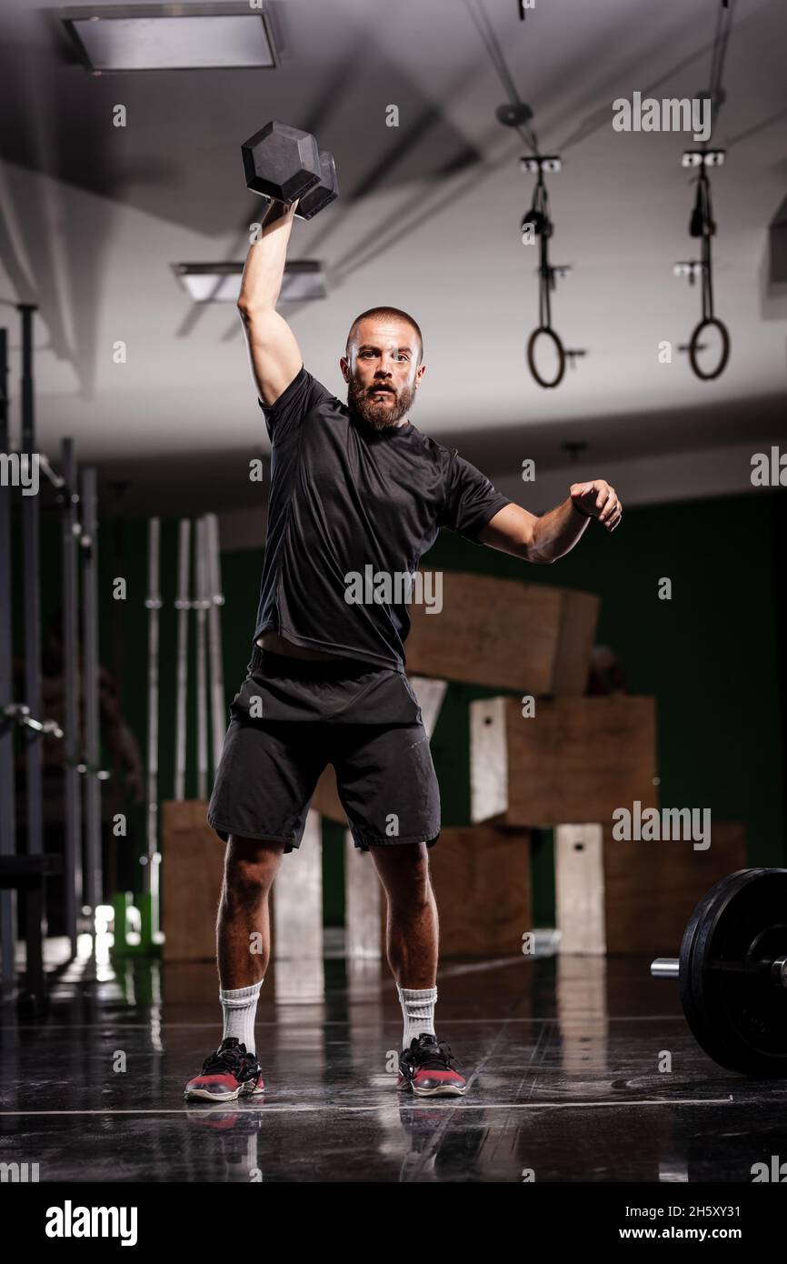 Muscular athlete lifting very heavy weights. Man working out indoors ...