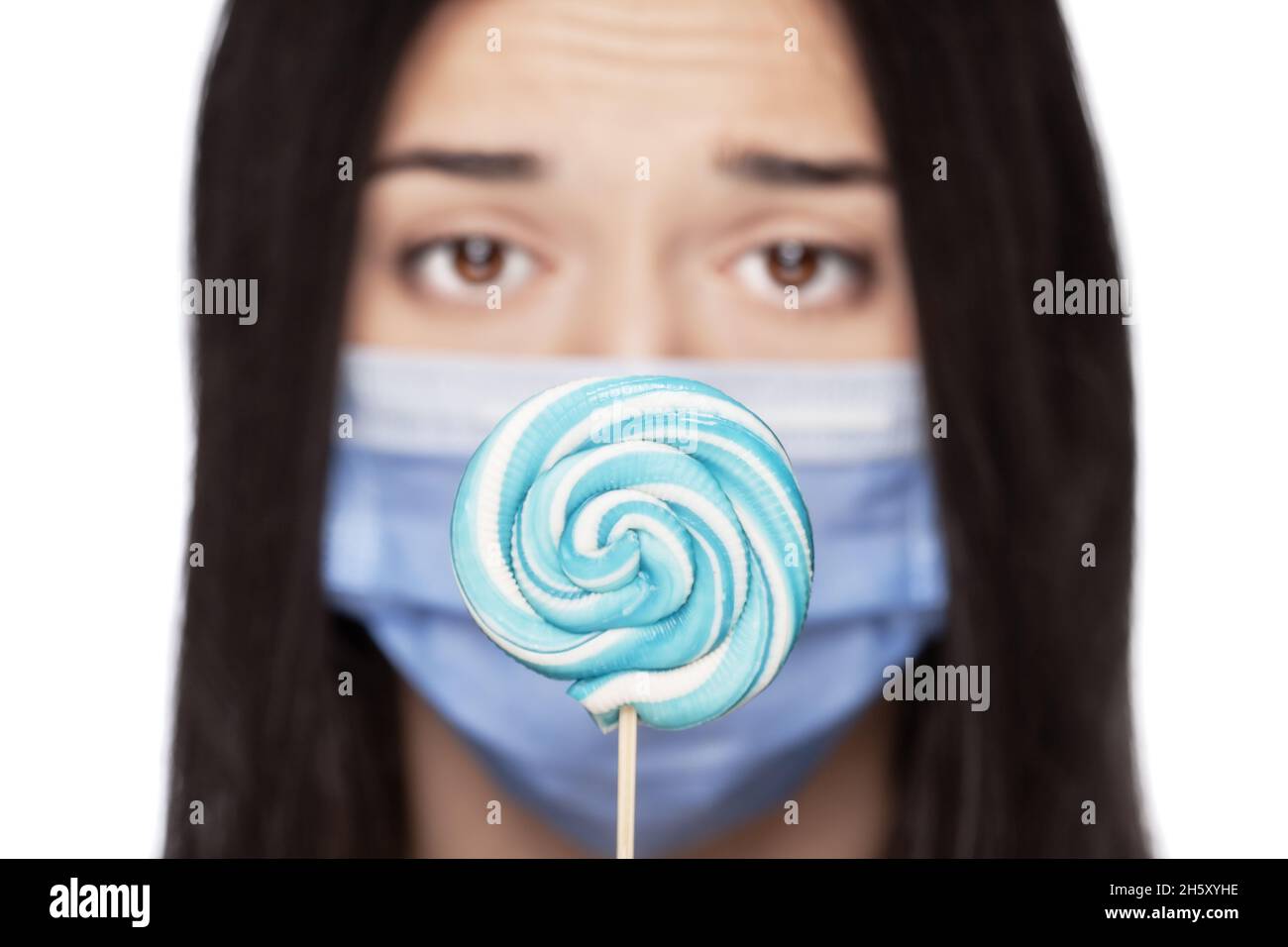 Sad girl having her mouth covered with with medical face mask holding ...