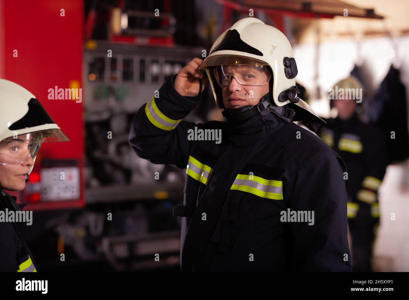 Professional firefighters with uniforms and protective helmets getting ...