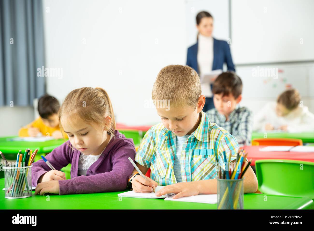 Portrait of schoolchildren sitting in classroom and chatting during ...