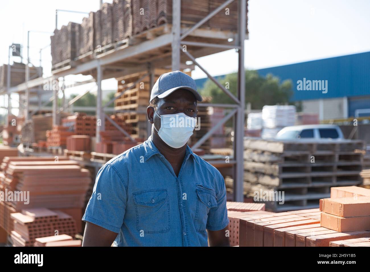 Male builder carrying bricks in outdoor warehouse Stock Photo - Alamy