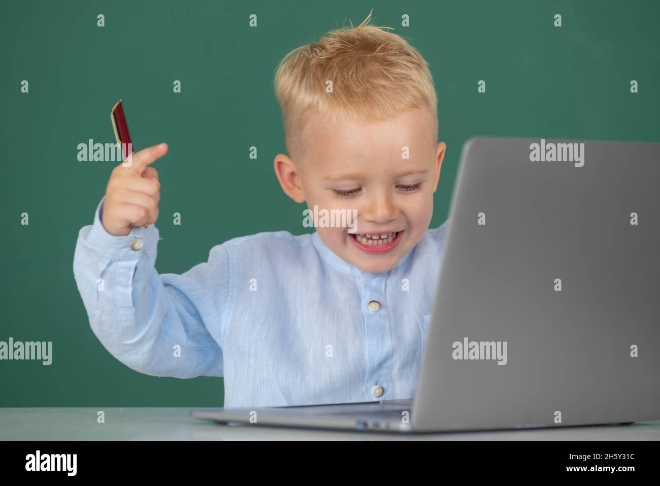 Excited little student boy using laptop computer in school class ...