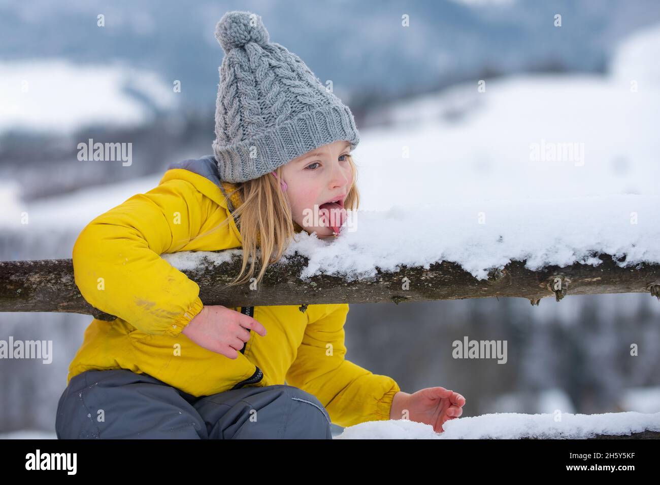 Winter girl eating snow outdoor. Funny christmas kids holiday. Kids ...