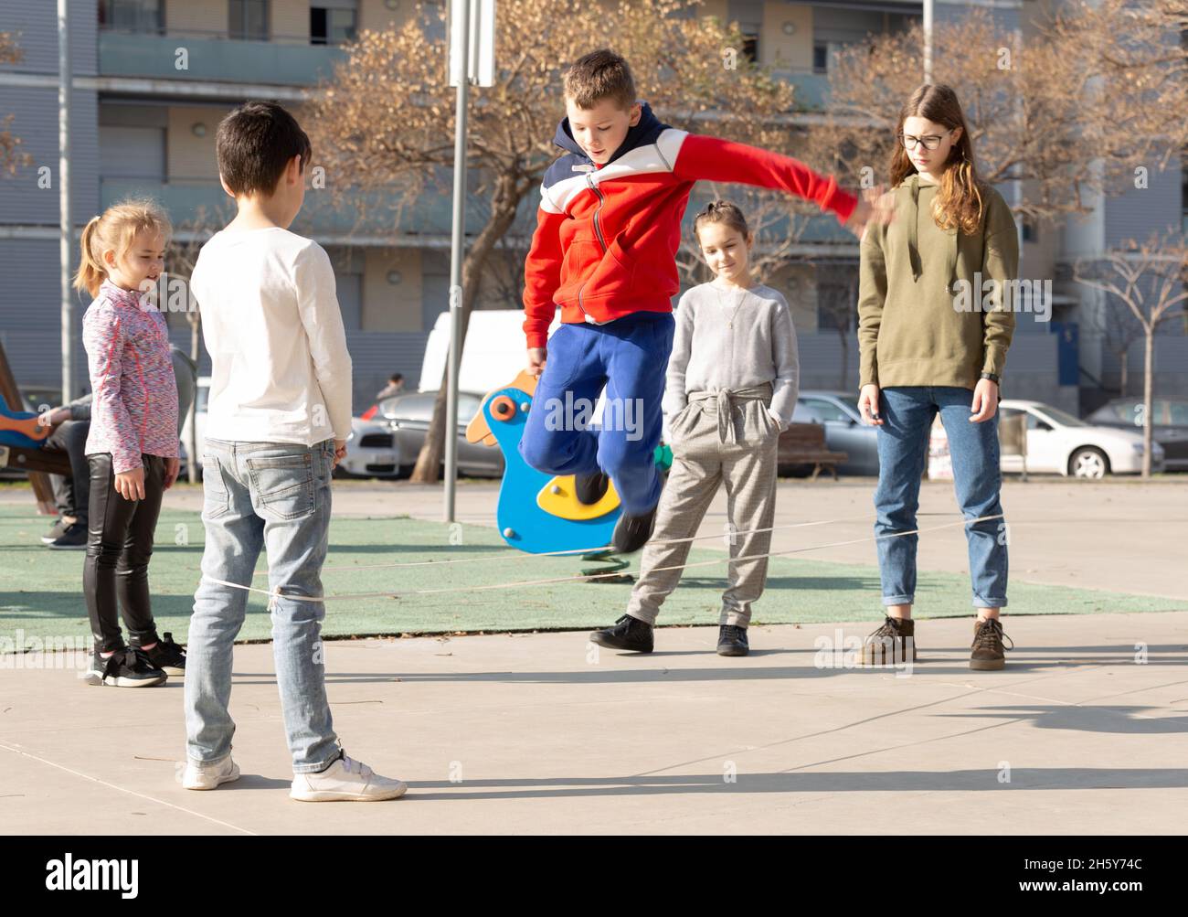 Children skipping on elastic jump rope Stock Photo - Alamy